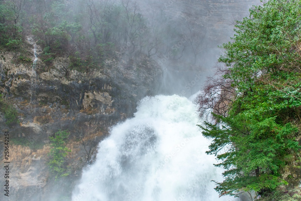 The rushing water of river in flood pours down a waterfall behind the ...
