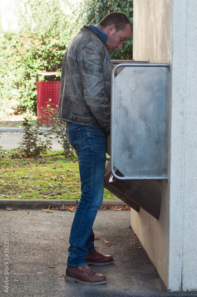 Foto de Stock portrait of man peeing in metallic public toilets for men ...