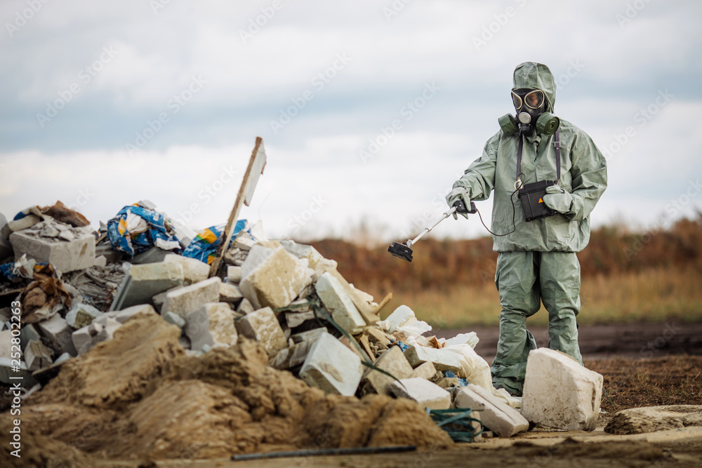 radiation supervisor in protective clothing and gas mask with geiger ...