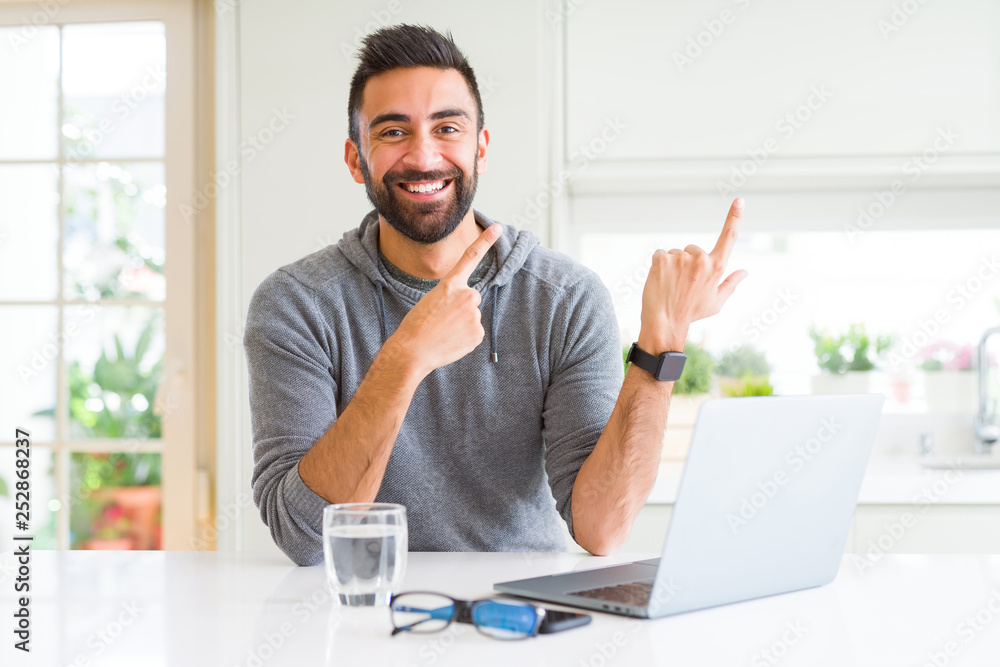 Handsome hispanic man working using computer laptop smiling and looking ...