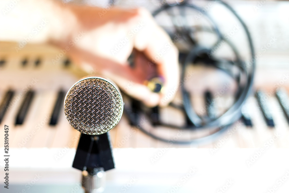 Silver microphone on rack closeup. Keyboard synthesizer and audio wires ...