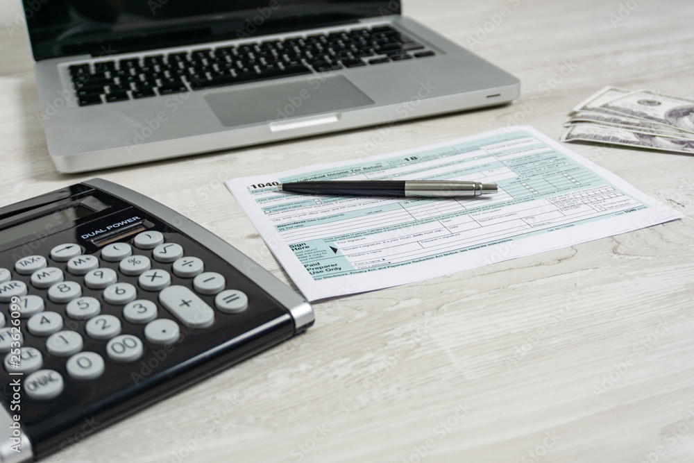 US tax form next to computer laptop, dollar bills, calculator and tax ...