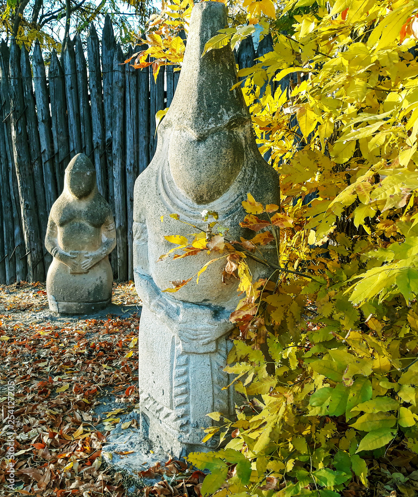 Stone balbal on background of yellow leaves. Ancient stone statue of a ...