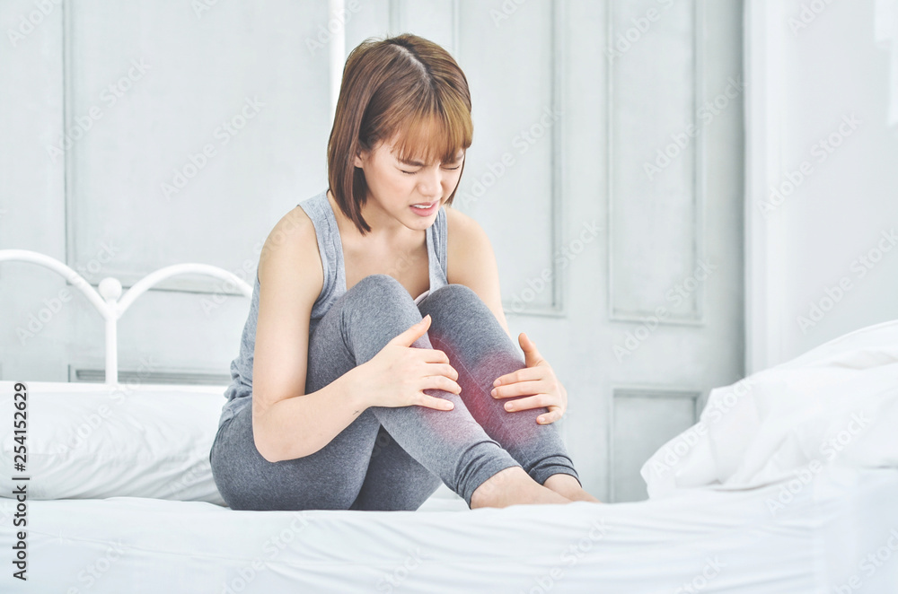 Asian girl wearing gray dress Have leg pain. The woman was squeezing ...