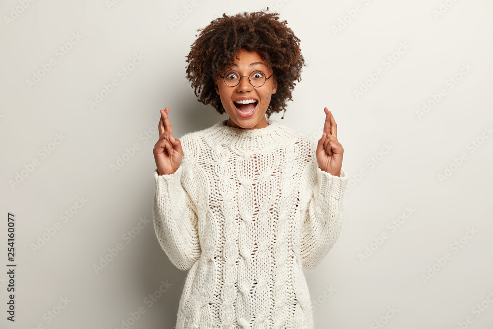 Positive emotional dark skinned young female crosses fingers for good ...