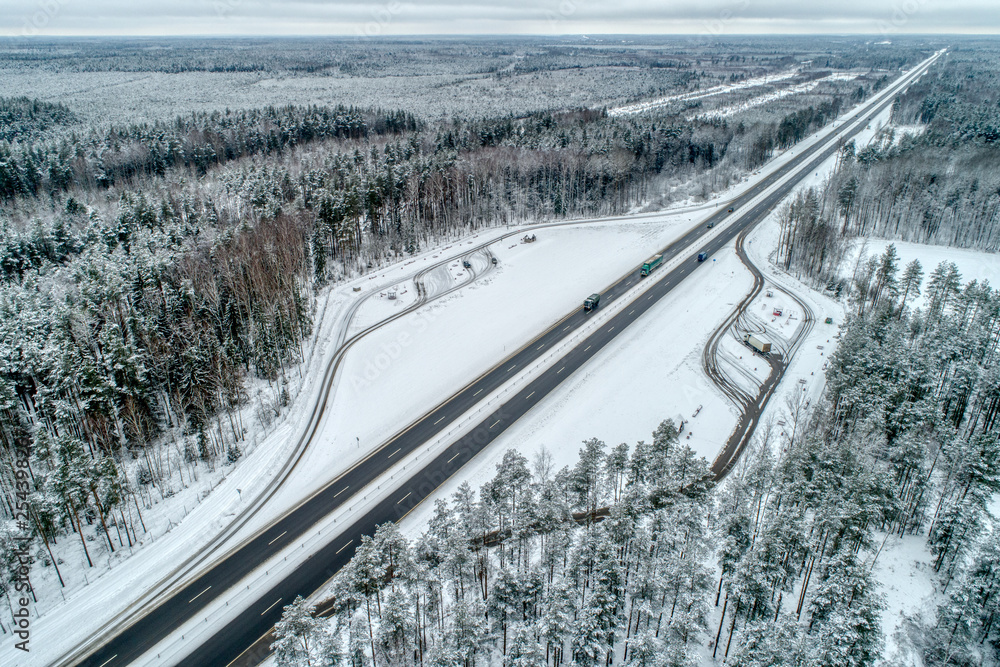 Freeway passing through the winter forest. The road goes away to the ...