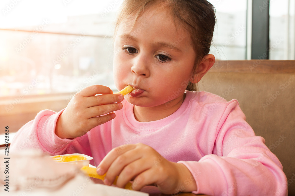 Little child eating a french fries in the cafe Stock Photo | Adobe Stock