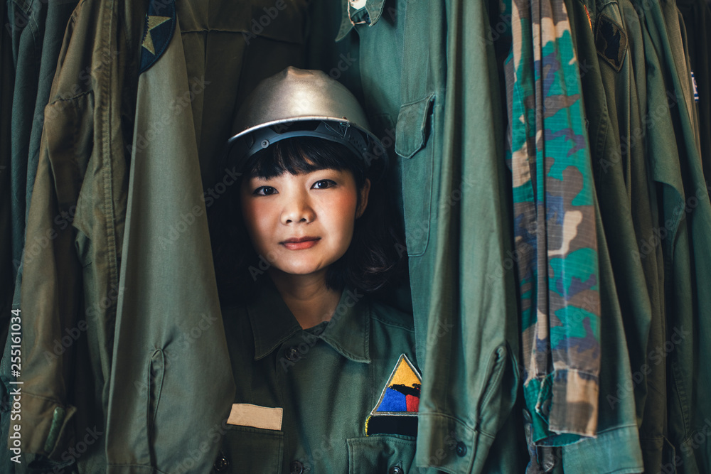 Portrait of Asian woman shop assistant sitting by the clothes rack and ...