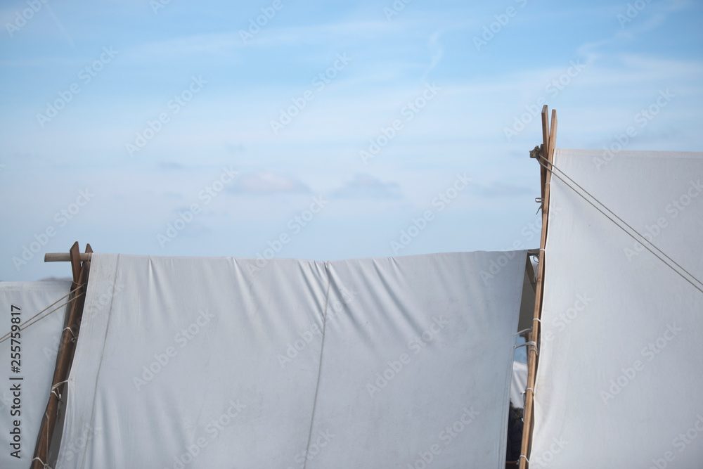 White cloth tent, tipi with wooden poles and blue sky with white clouds Stock Photo | Adobe Stock
