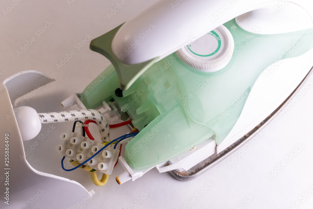 Repair of household appliances. Disassembled green electric iron. The ...