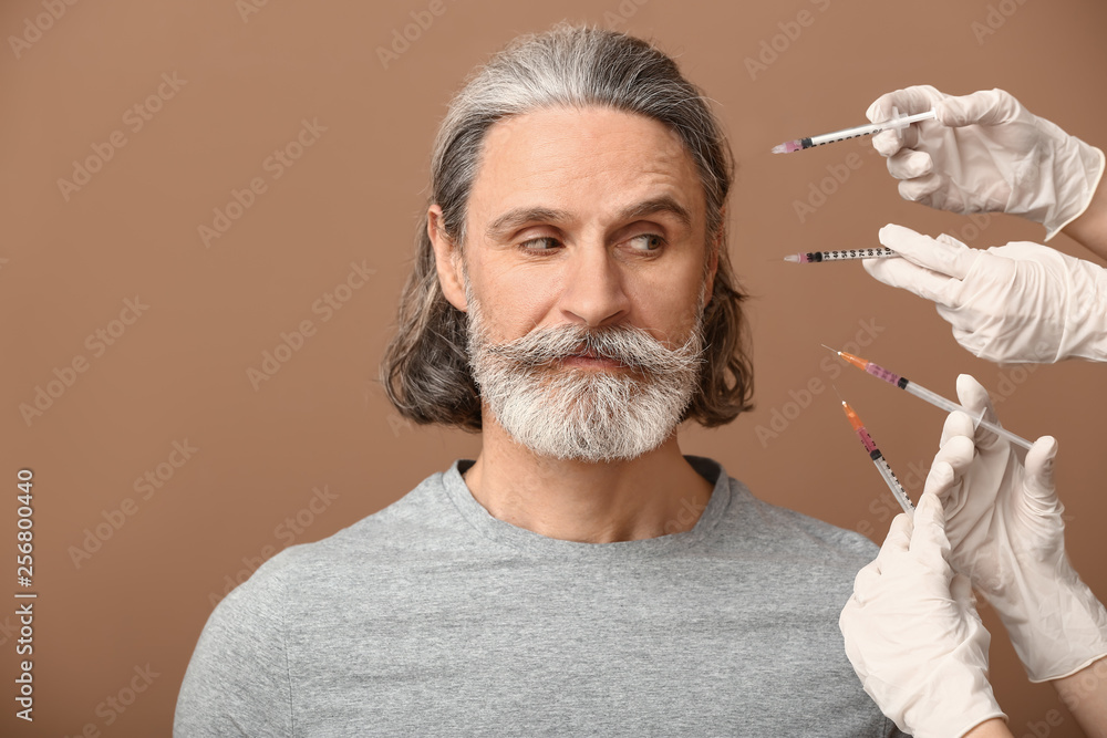 Mature man and hands holding syringes for anti-aging injections on ...