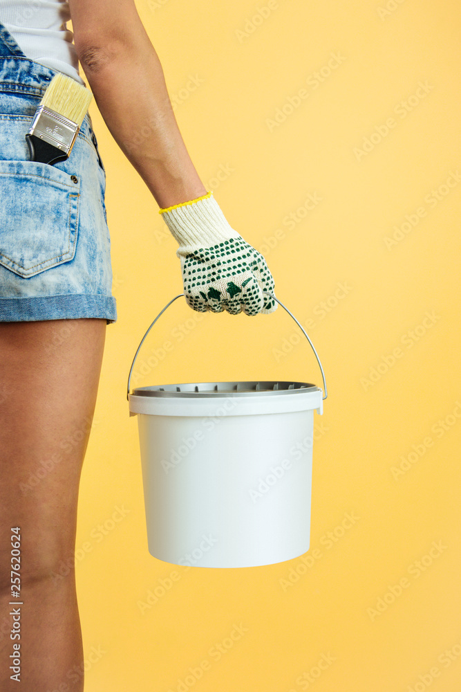 Beautiful woman holds in hand a white bucket with paint ready to start ...