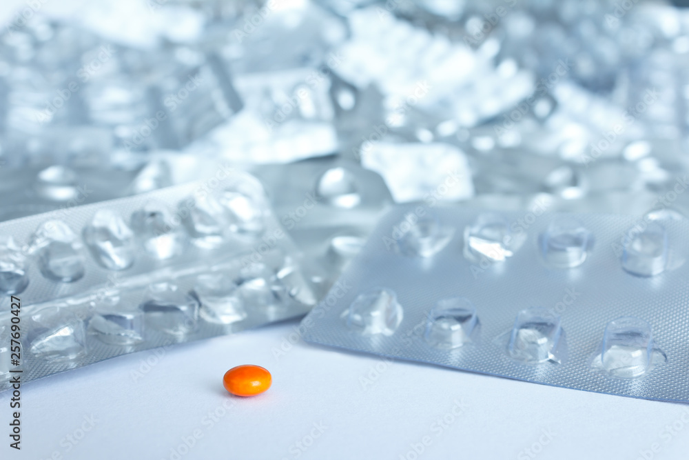 One single pill in front of many empty blister packages on white ...