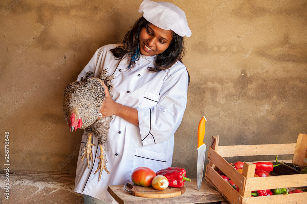 Attractive Indian woman cook posing in kitchen with chicken in her ...