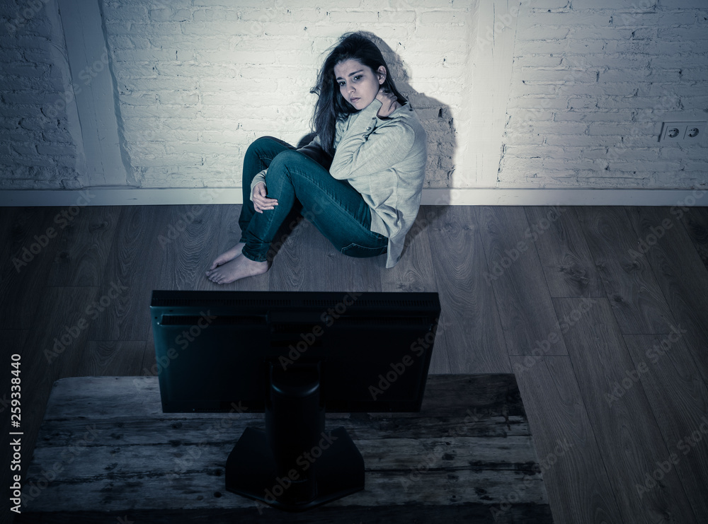 Scared and sad young woman on the floor staring a computer suffering ...