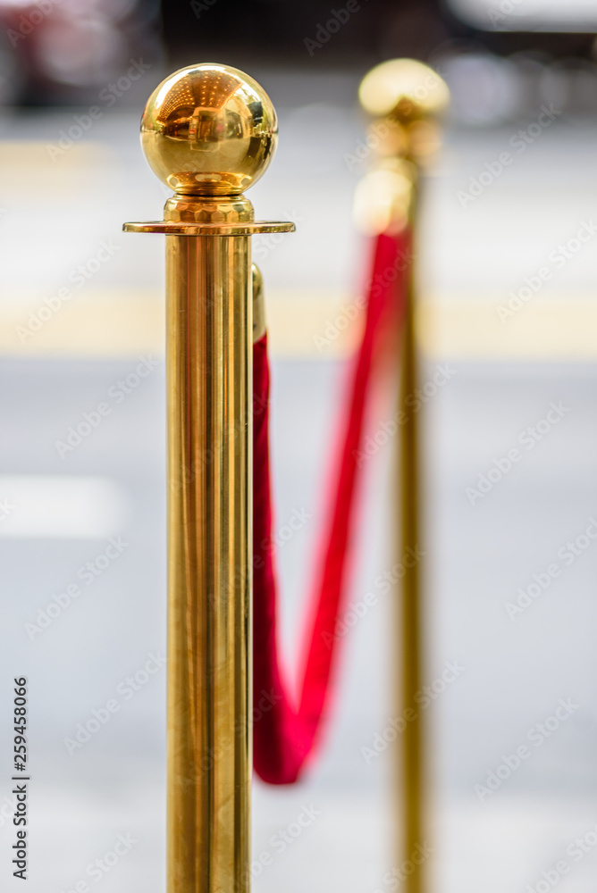 Gold metal posts holding a red velvet rope as is often used at event ...