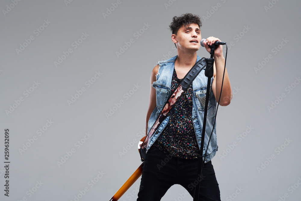 Portrait of rock singer man keeping electric guitar and static acoustic ...