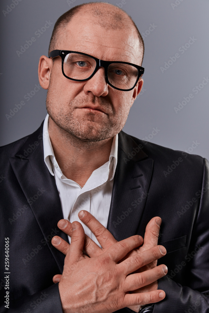 Thinking sad bald business man holding the chest two hands with serious ...