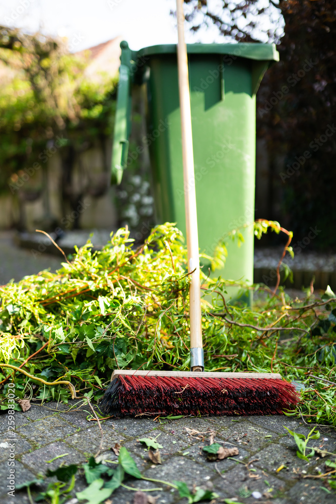 Green wheelie bin / garden waste container and broom filled with fruit ...