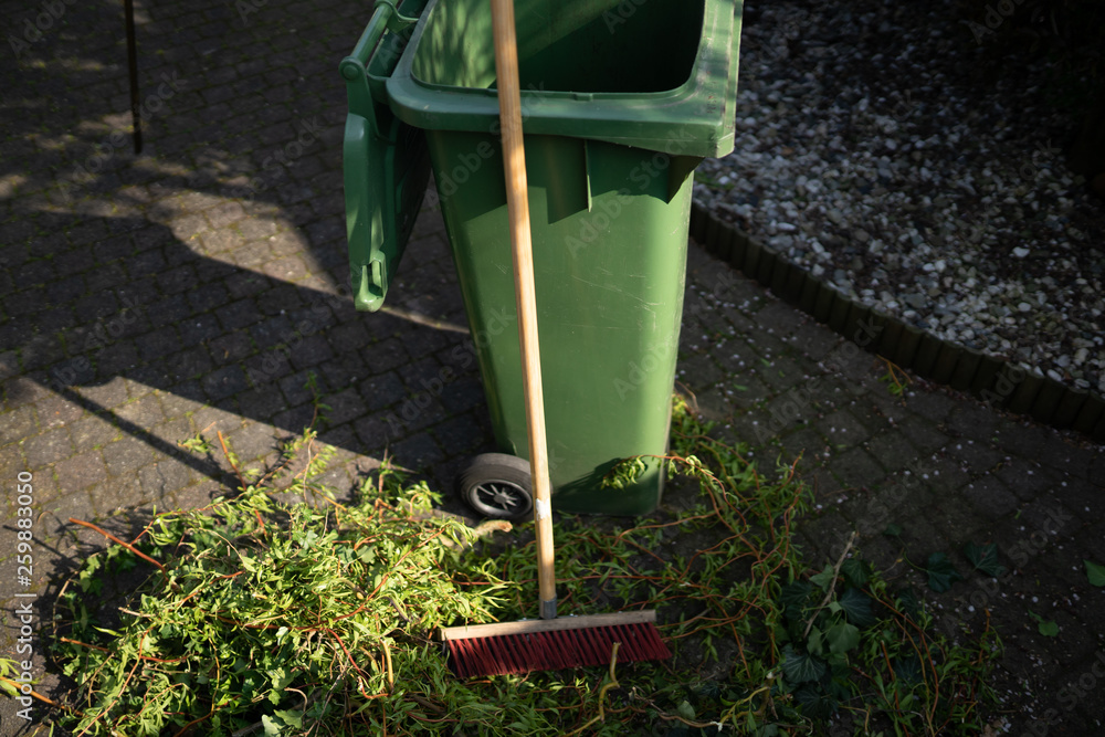 Green wheelie bin / garden waste container and broom filled with fruit ...
