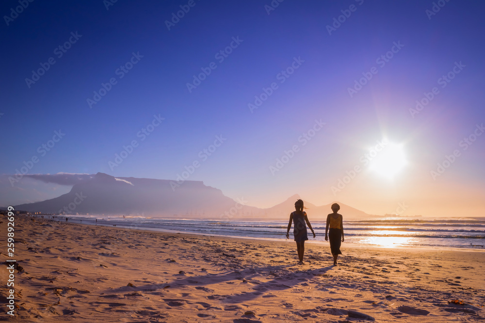 Photo Stock Two African women dancing on the beach at sunset, with ...