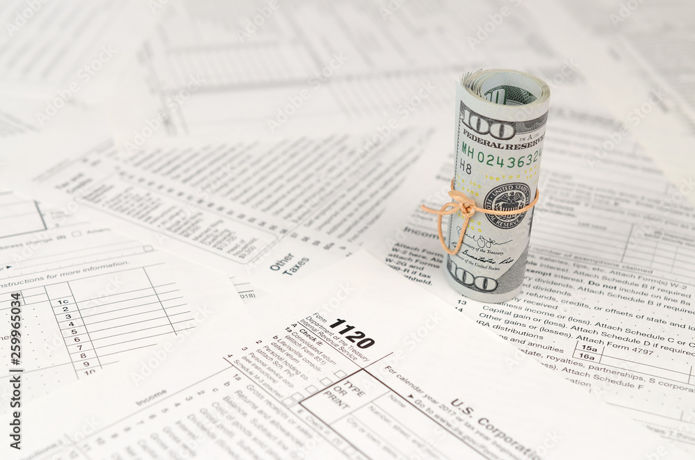 1120 U.S. Corporation income tax return form with roll of american ...