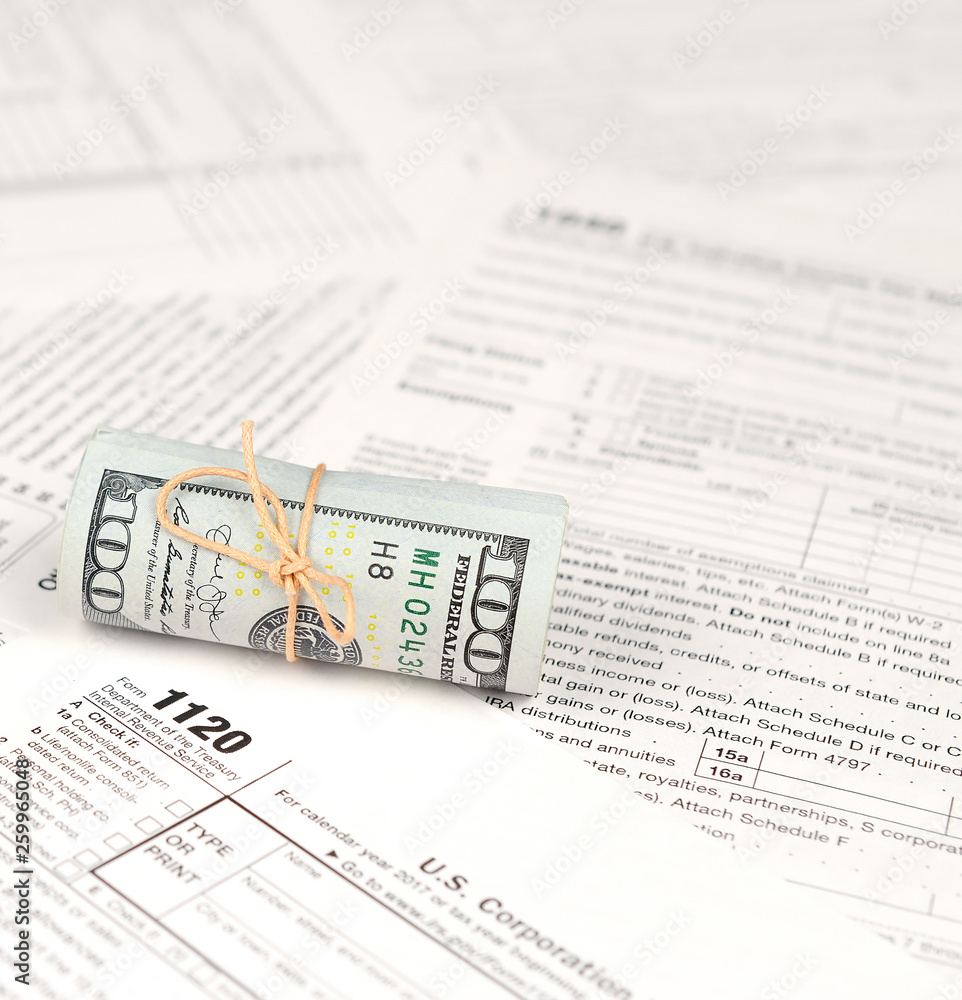 1120 U.S. Corporation income tax return form with roll of american ...