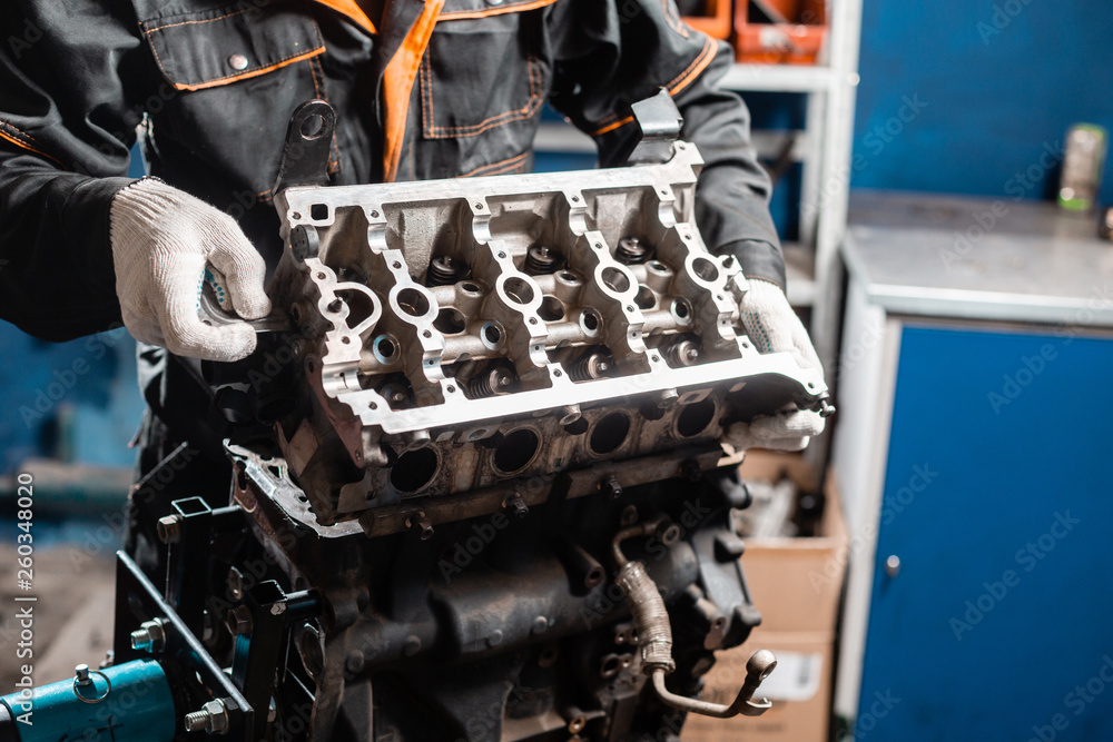 Mechanic disassembling the engine, overhaul.. Engine on a repair stand ...