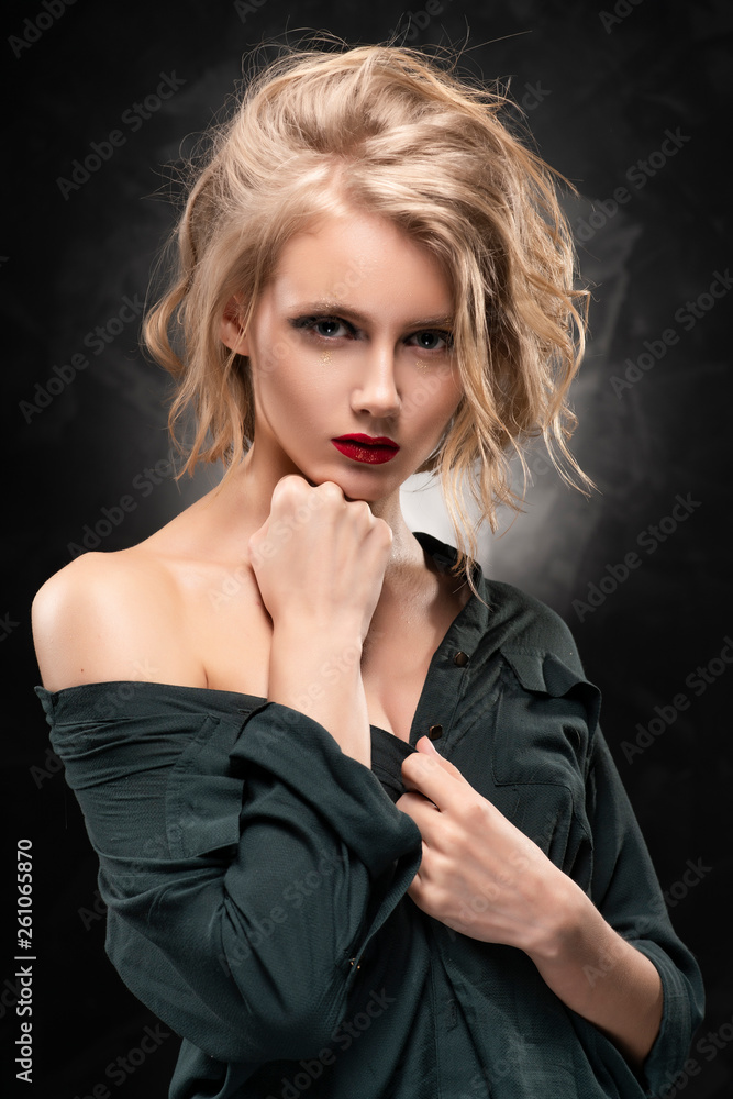 Beautiful young braless slim blonde girl with disheveled hair and aggressive makeup, wearing an ...