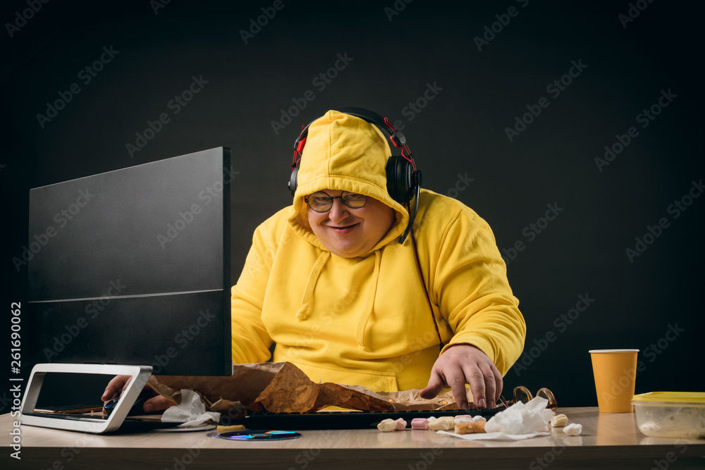 Funny guy in yellow hoody getting pleasure from online games. close up photo. isolated black ...