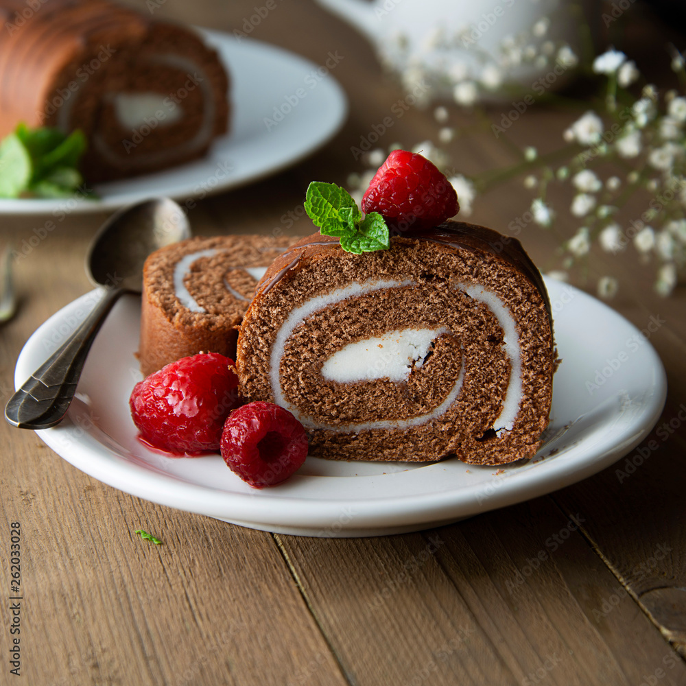 Delicious chocolate roll sponge cake with vanilla cream and mint leaves ...