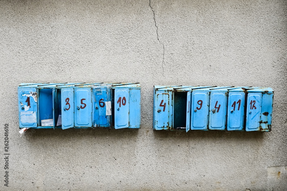 Old rusty mailboxes on the wall. Blue broken mailboxes with numbers ...