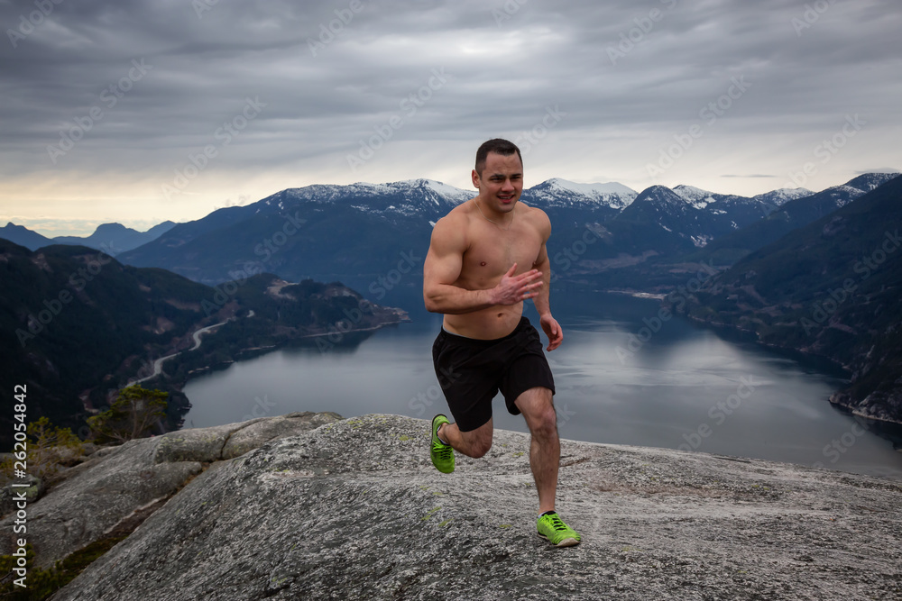 Fit and Muscular Young Man is Running up the Mountain during a cloudy ...