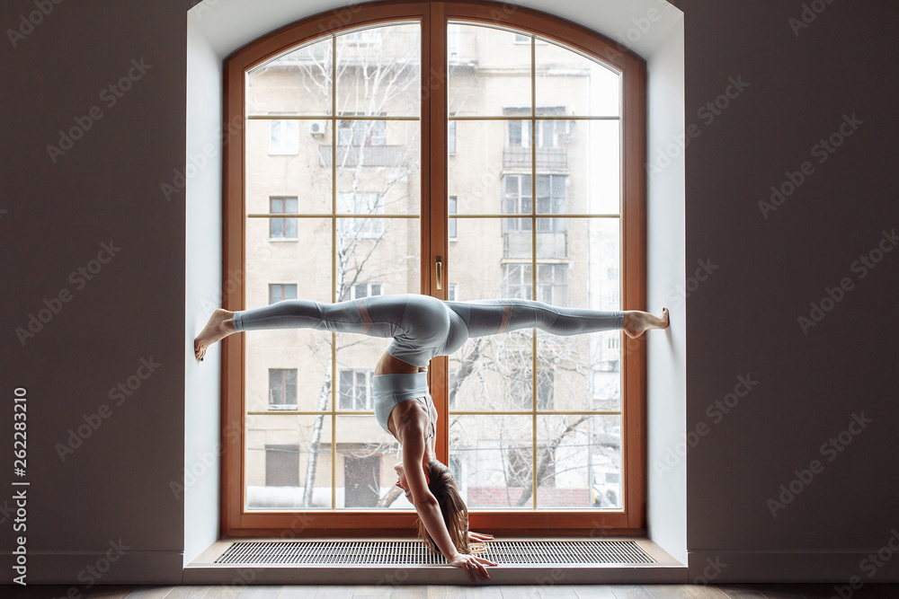 Fit young girl in a gymnastic costume makes an inverted split in the ...
