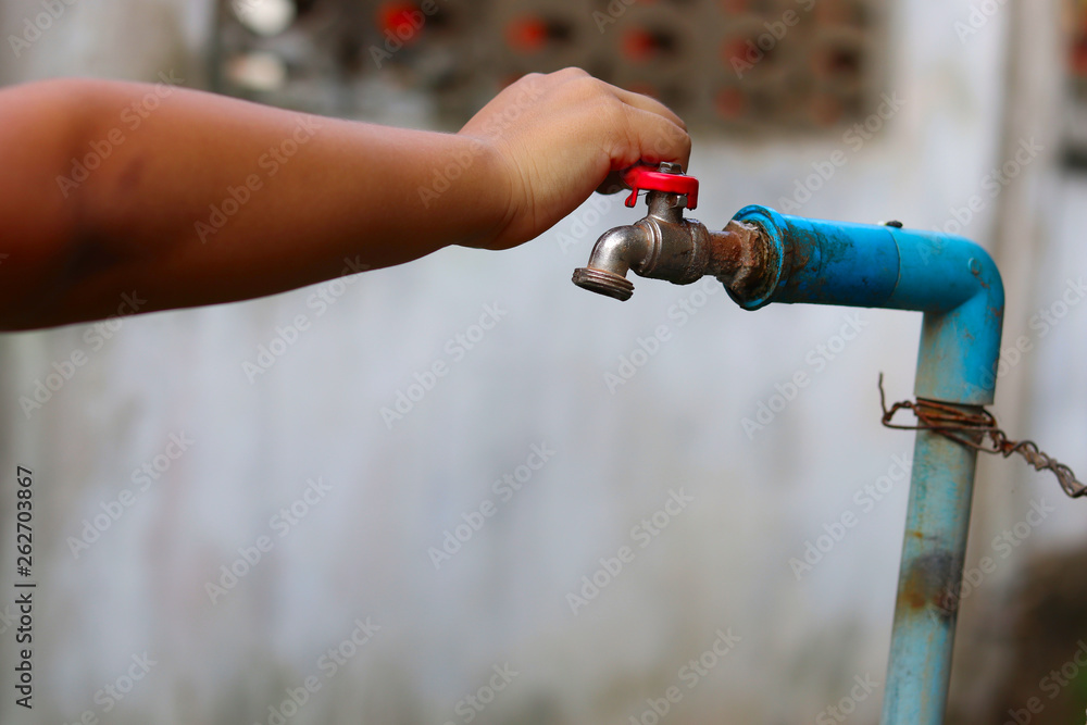 Young hands turning off an old rusty water tap for saving water - save ...