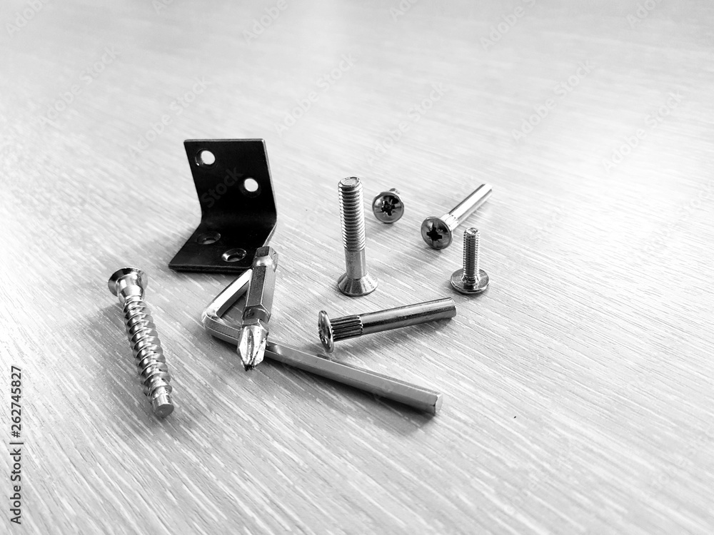 Different fasteners and hardware lie on a light wooden texture with ...