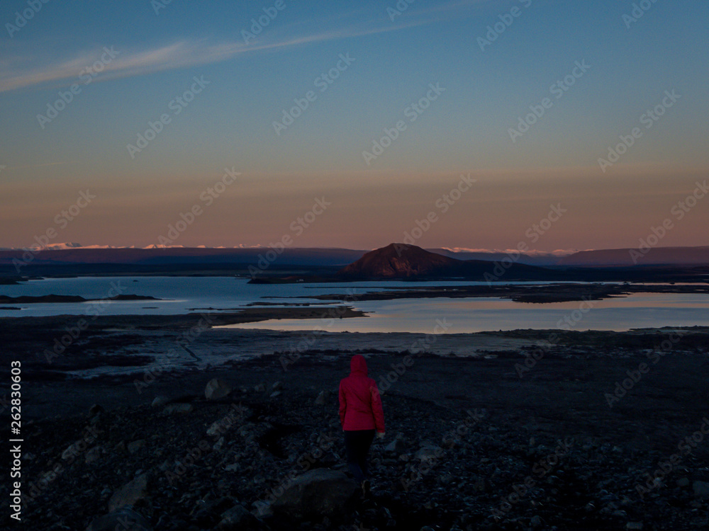 Girl wearing pink jacket walks around the top of the volcano. Sunrise ...