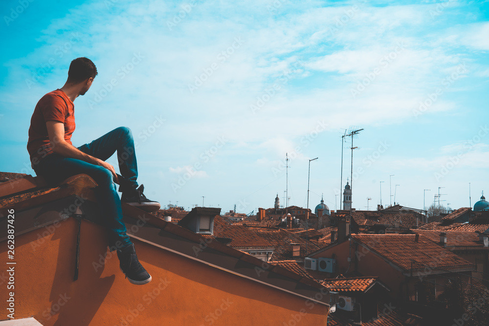 Young man sitting on the rooftop in Venice exploring the city from ...