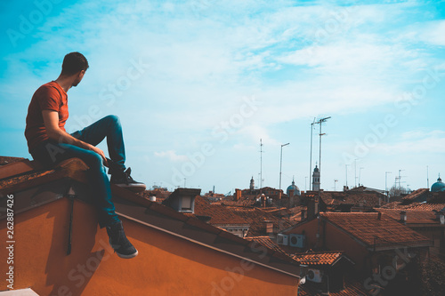 Young man sitting on the rooftop in Venice exploring the city from ...