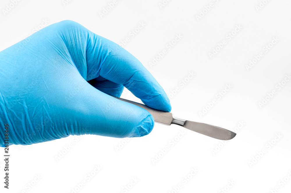 Surgical instruments and surgery concept with hand wearing blue latex ...