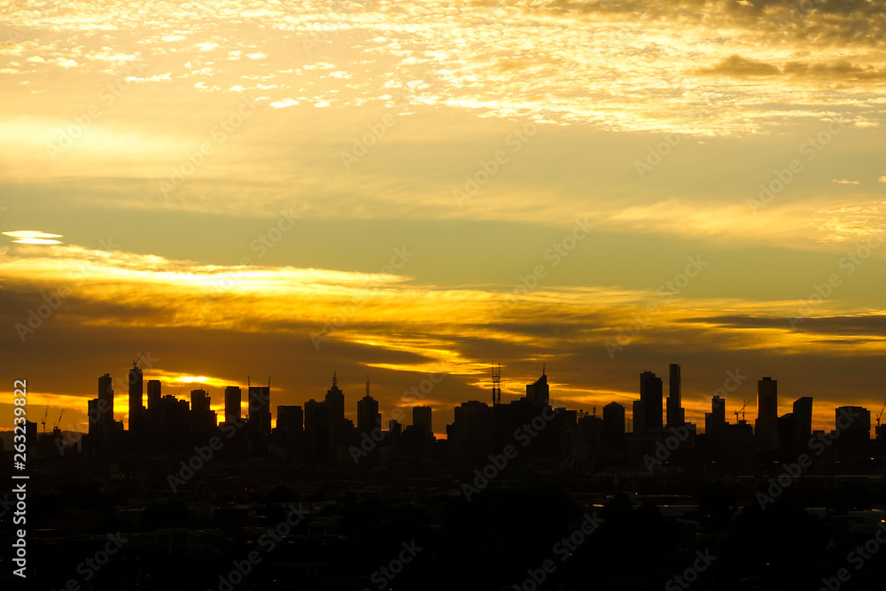 Silhouette of Melbourne city landscape against dramatic golden yellow ...