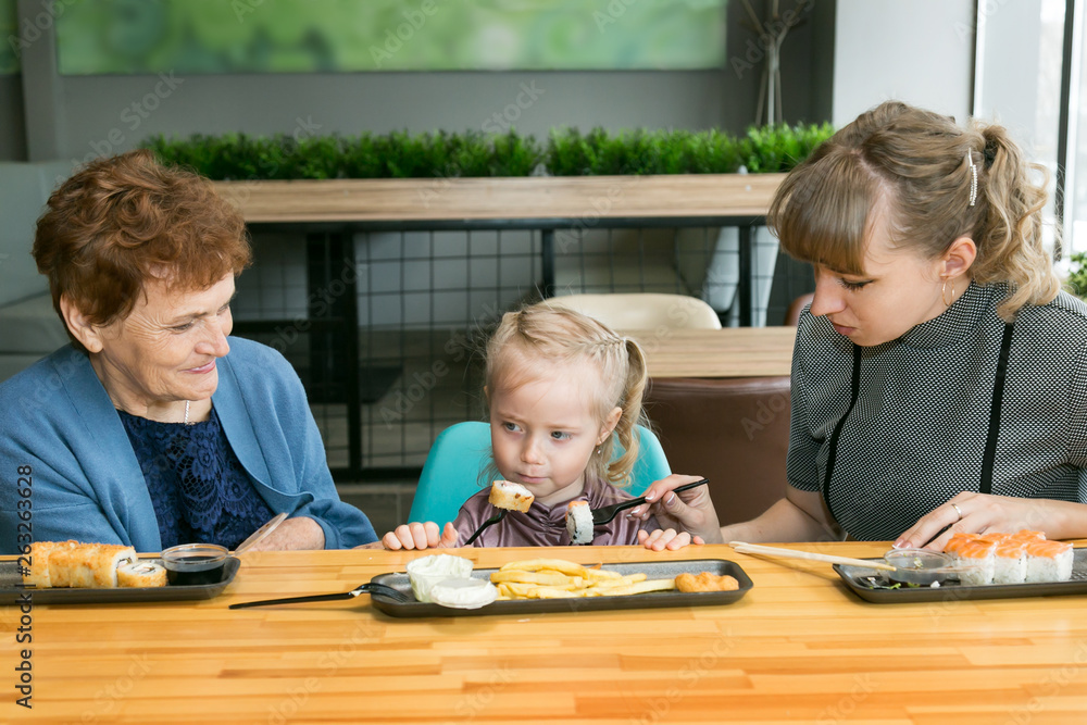 Mom and grandmother feed the little girl together. child does not want ...