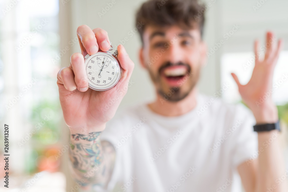 Young man using holding stopwatch very happy and excited, winner ...