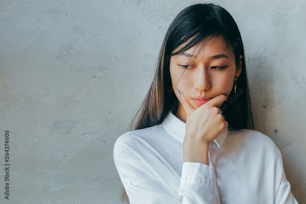 Thoughtful doubtful Beautiful asian girl in white shirt with unsure ...