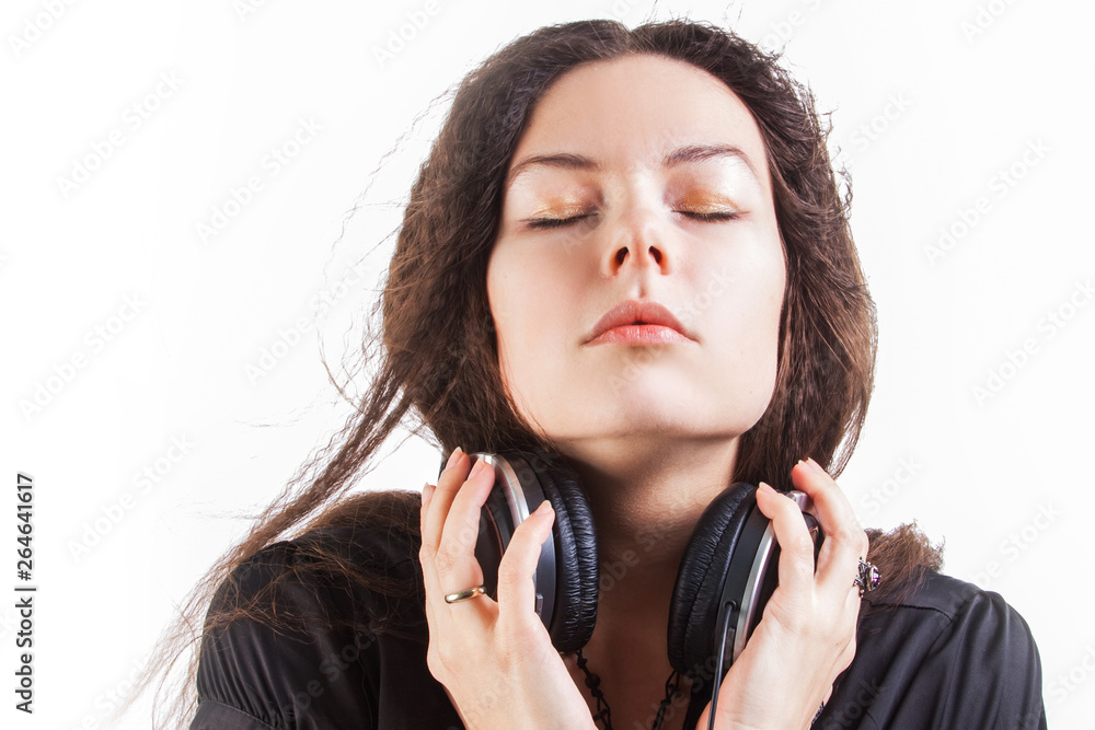 Young brunette woman in large headphones listening to music and having ...