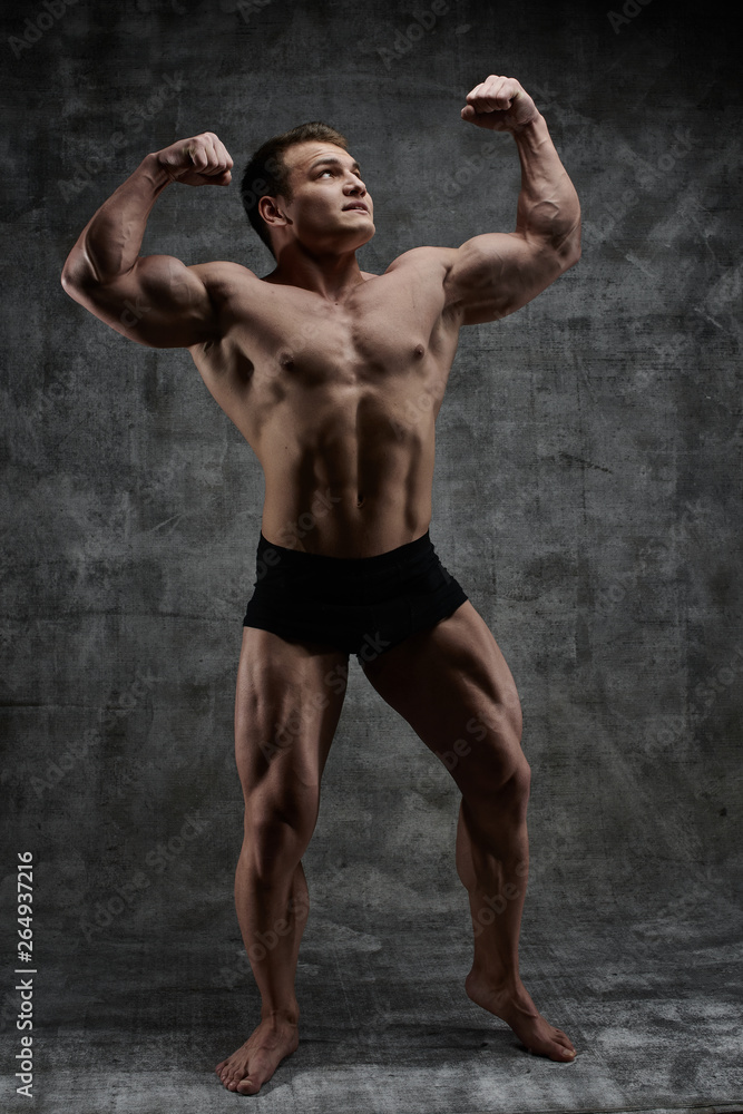 Sexy Bodybuilder Man Posing In Full Growth On Dark Background In Black