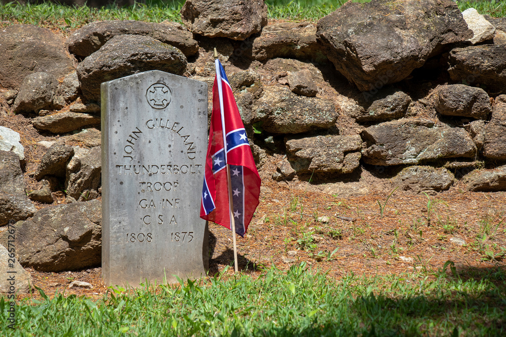 A Confederate flag and inscribed stone mark the grave of a veteran of ...
