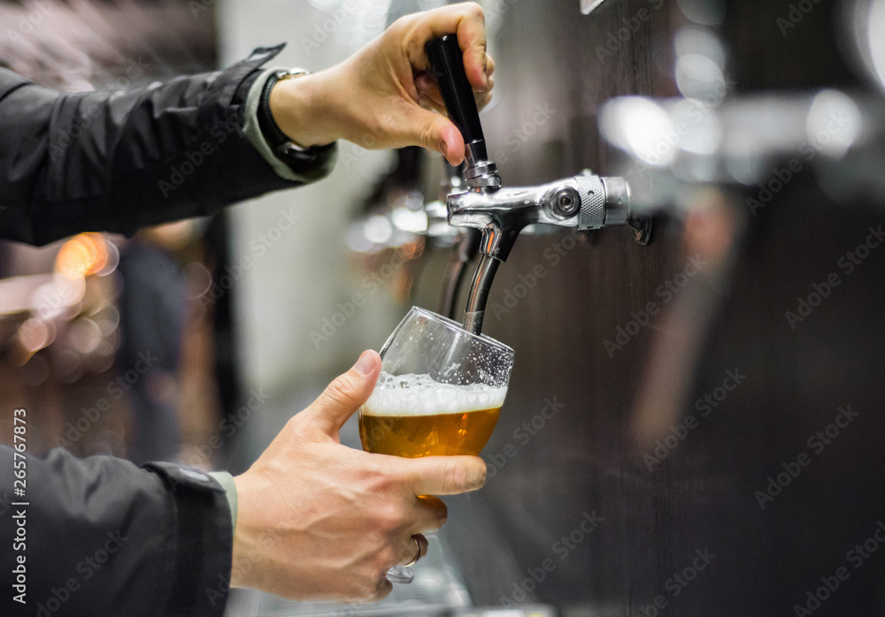 Stock-Foto „bartender hand at beer tap pouring a draught beer in glass serving in a restaurant ...