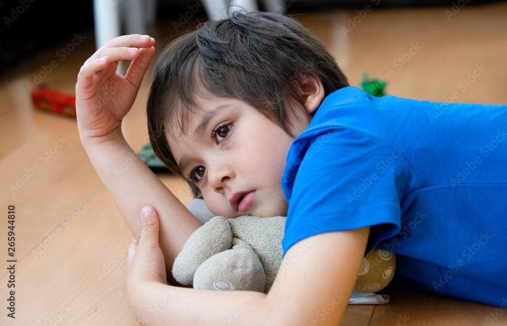 Foto de Stock Sad boy cuddle teddy bear laying down on loor in play ...