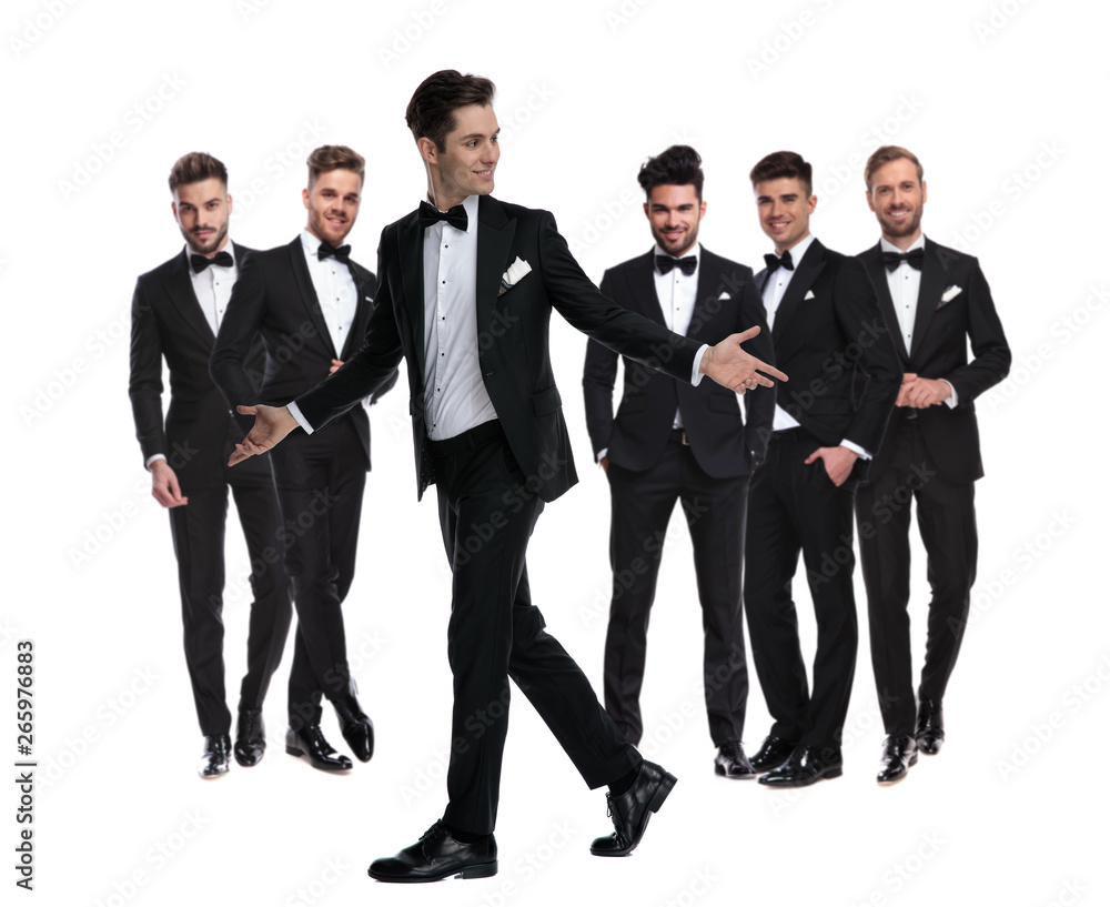 smiling man in tuxedo walks and welcomes while looking back Stock Photo ...
